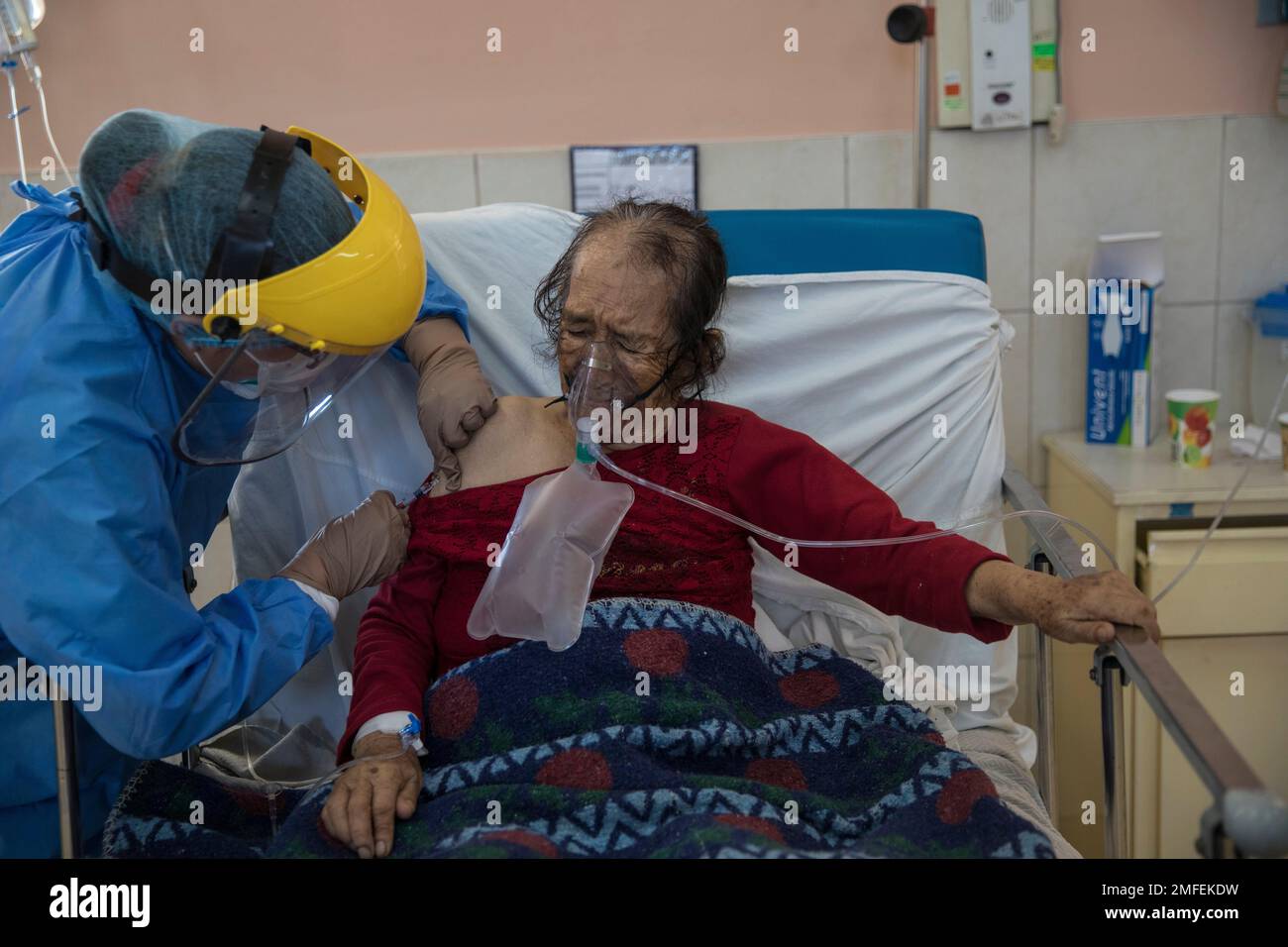 A nurse gives an injection to a patient inside the intensive care unit ...