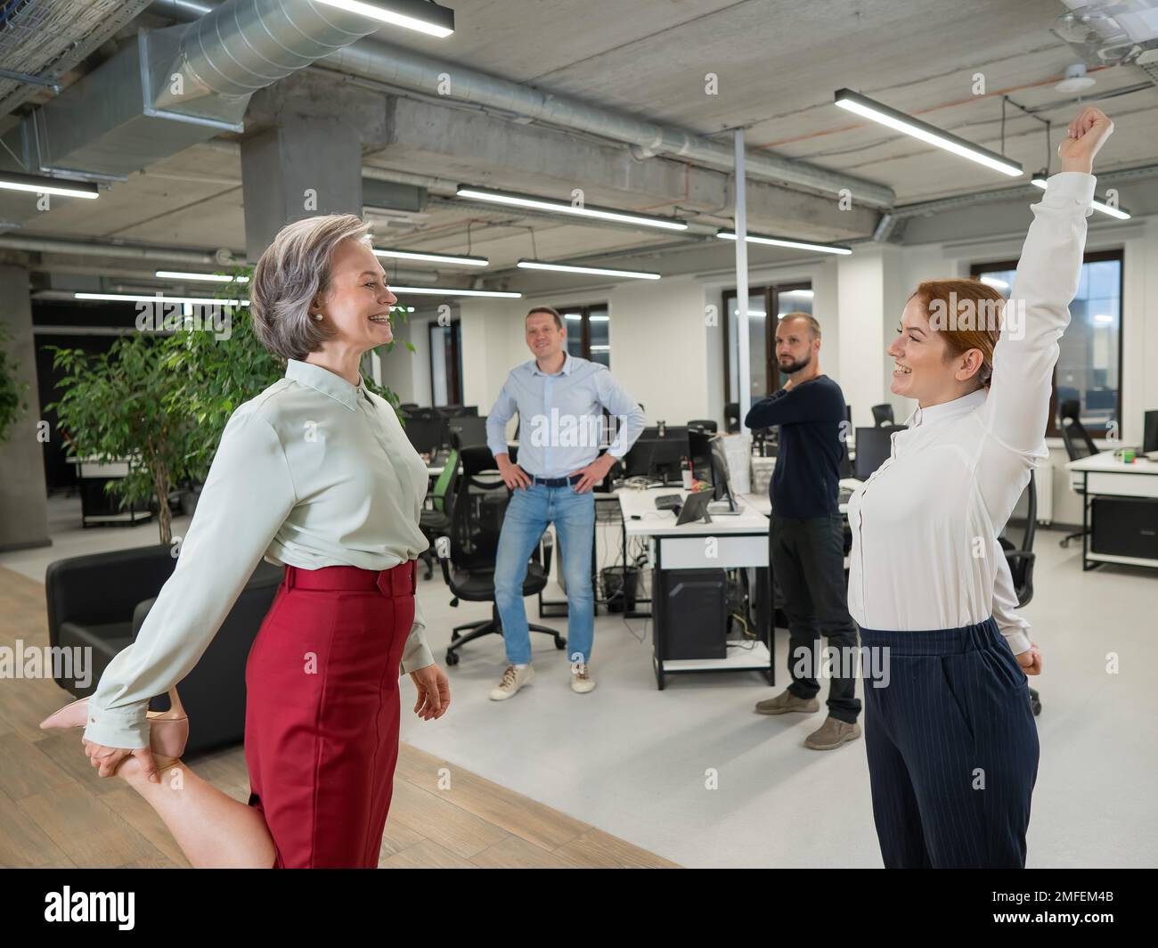 Four office workers warm up during a break. Employees do fitness ...