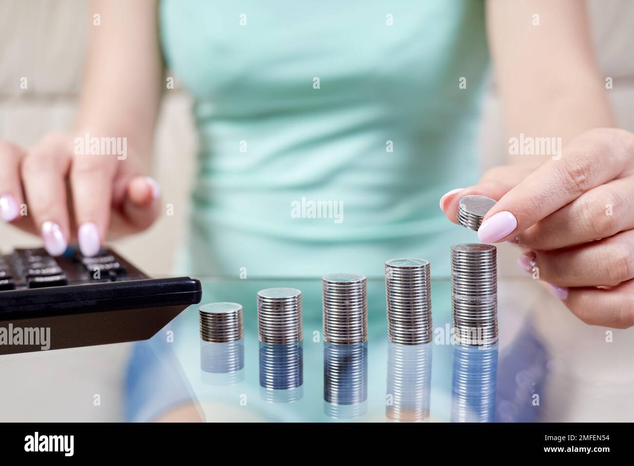 Woman puts coins to a stack of coins and counting on a calculator Stock ...