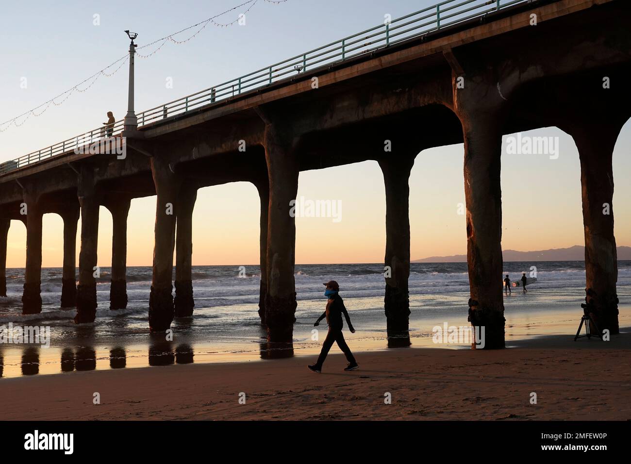 A visitor wears a face mask as she strolls along the beach during the ...