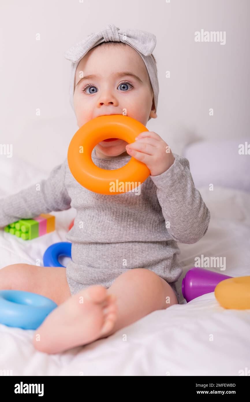 happy cute baby girl 7 months old at home on the bed playing with ...
