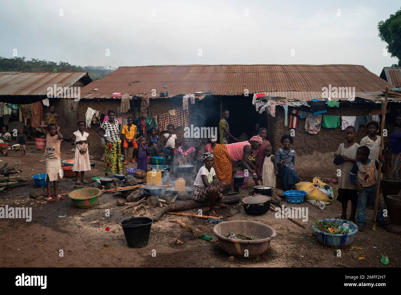 A woman cooks rice, center right, as people look at the camera in Komao ...