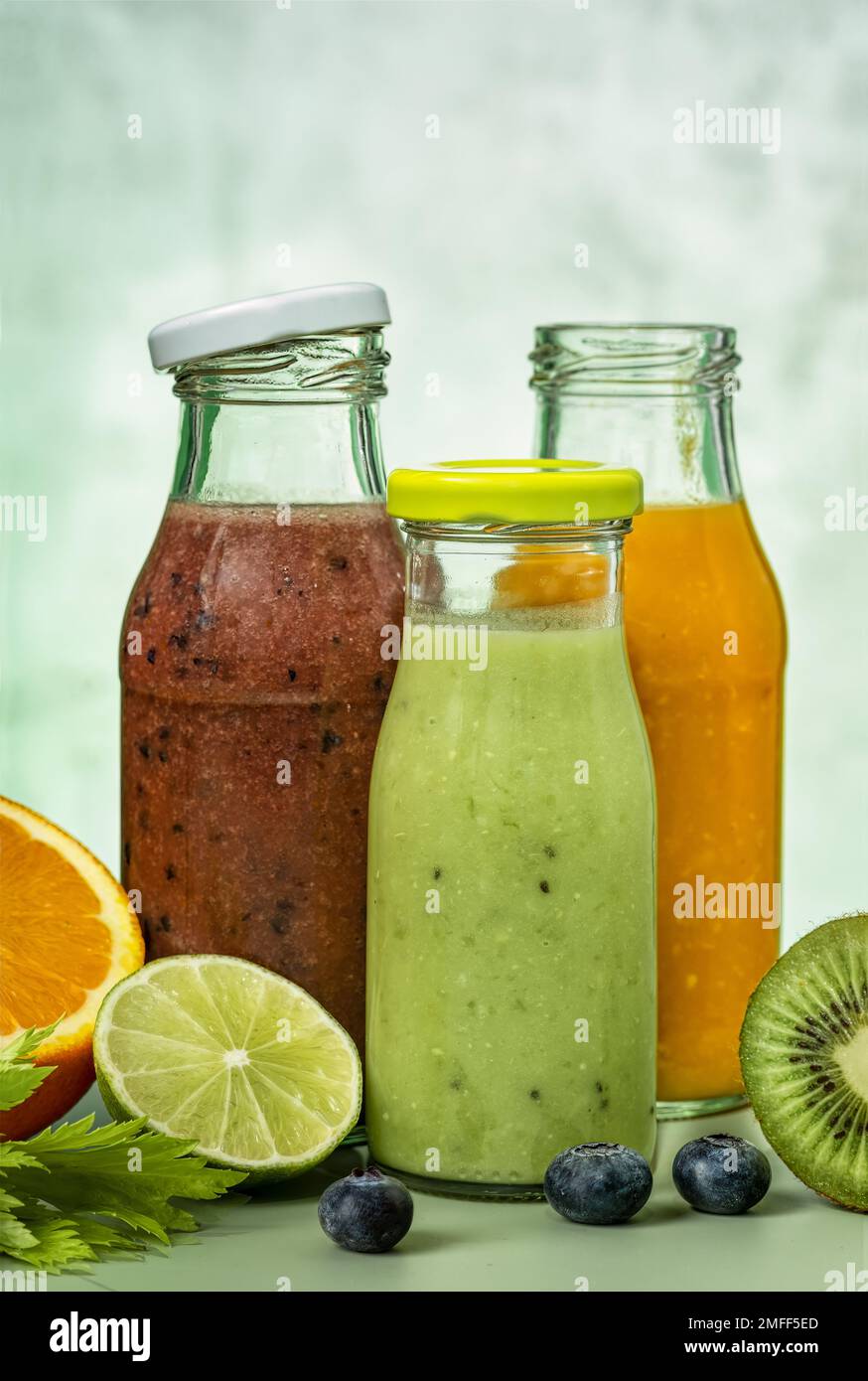 Green, orange and red smoothie in glass bottles Stock Photo - Alamy