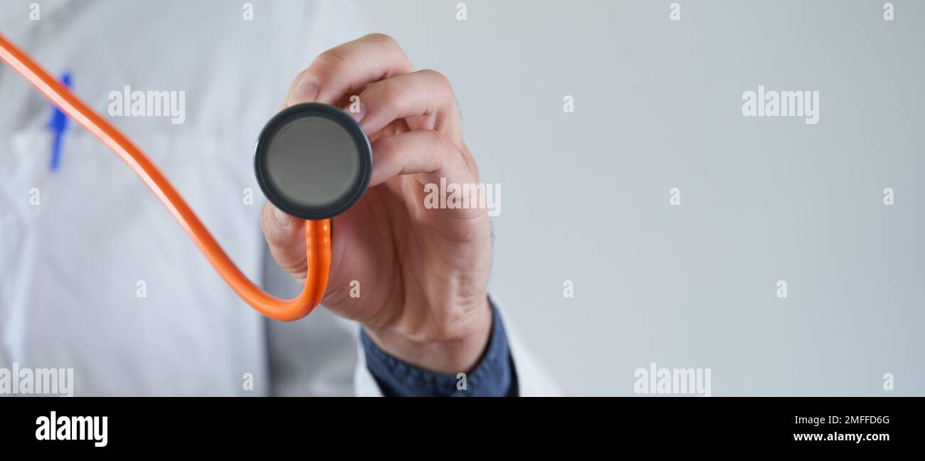 Health care concept. Doctor hand holding orange stethoscope over grey ...
