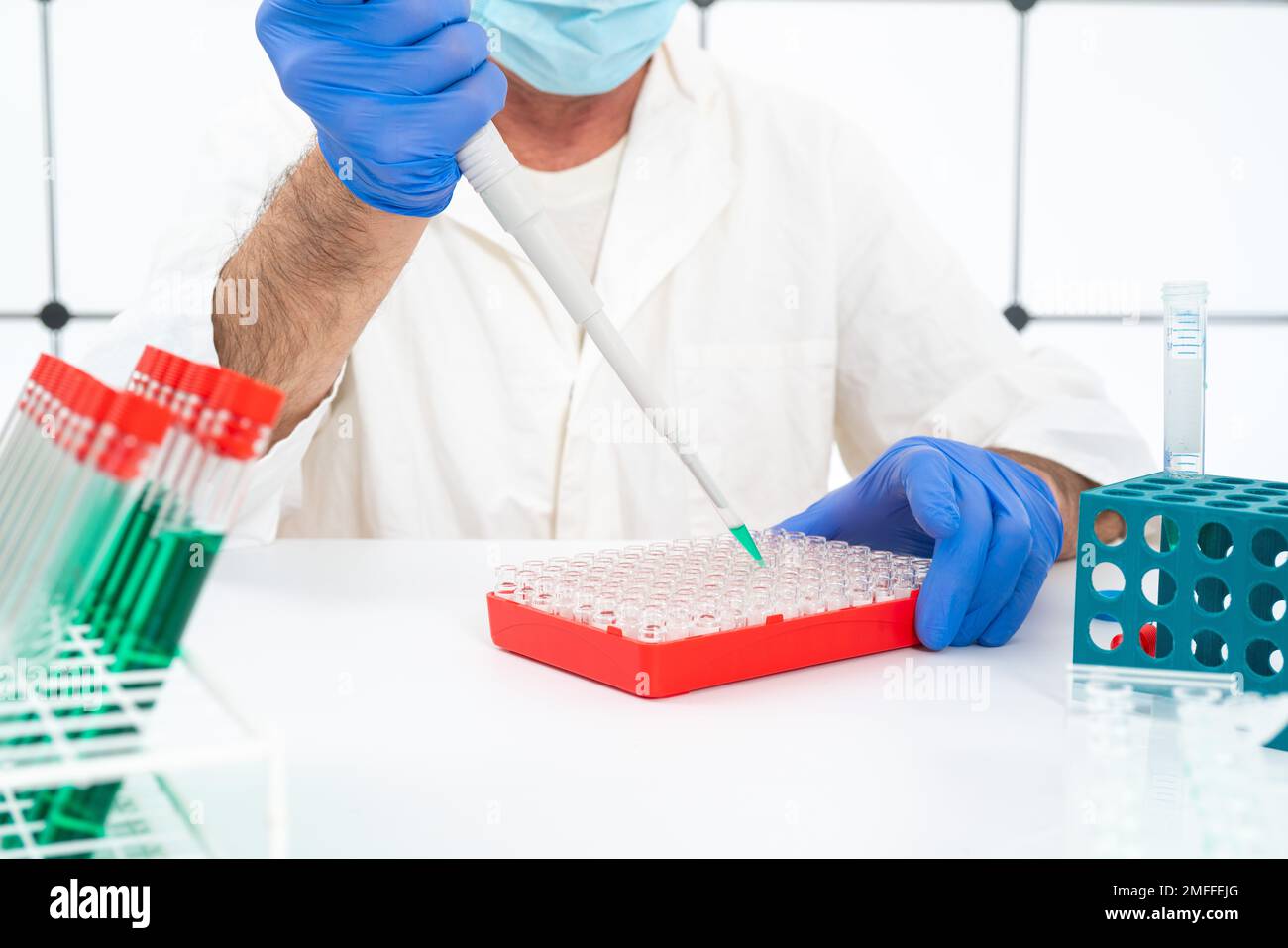 male laboratory assistant works with automatic pipette filling glass ...
