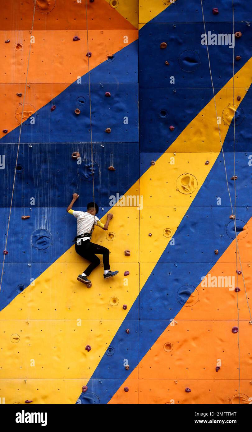 A boy climbs an artificial wall during a two-day-long sports climbing ...