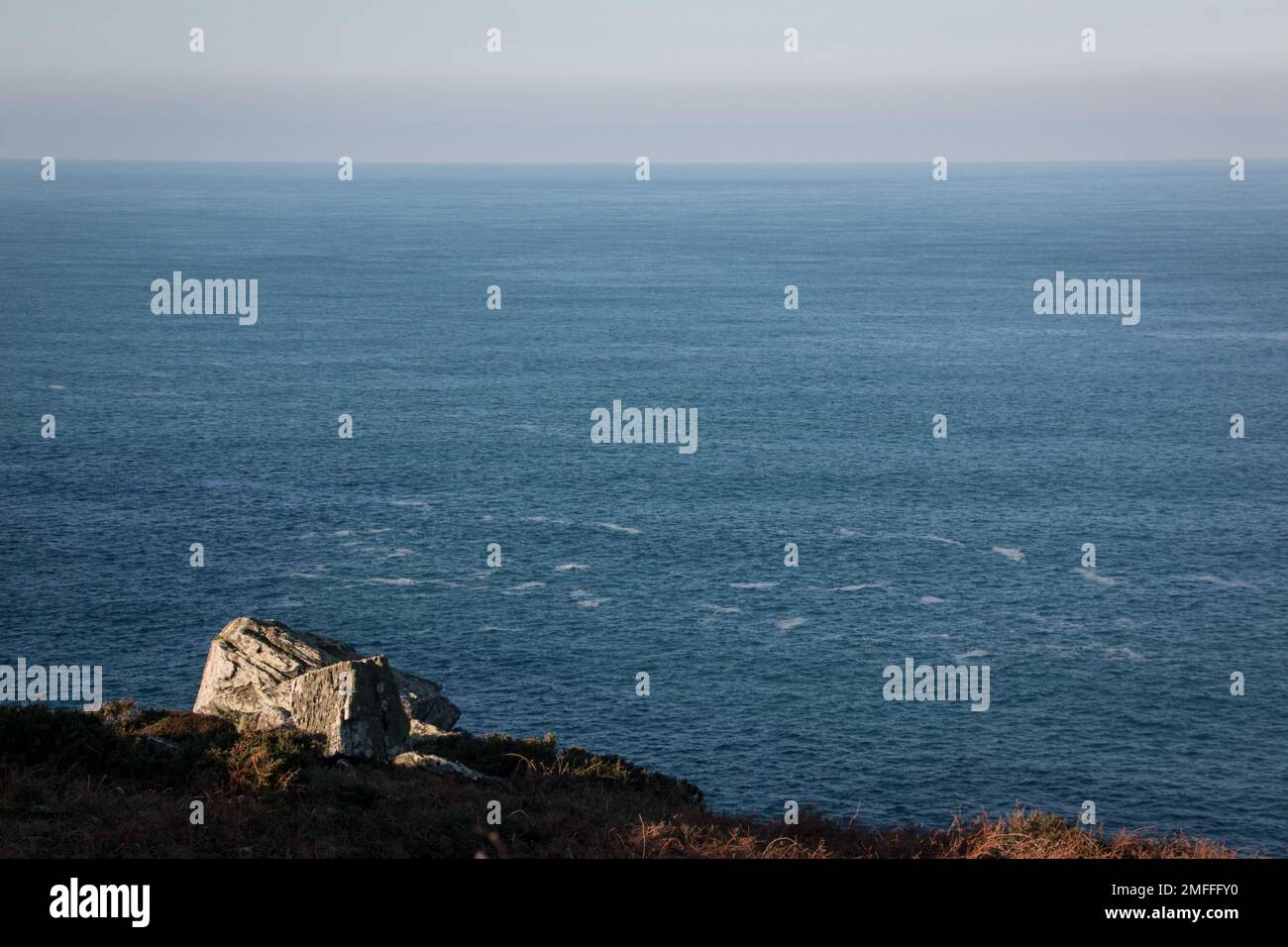 Jagged rock on cliff with negative space, sea and horizon behind, space ...