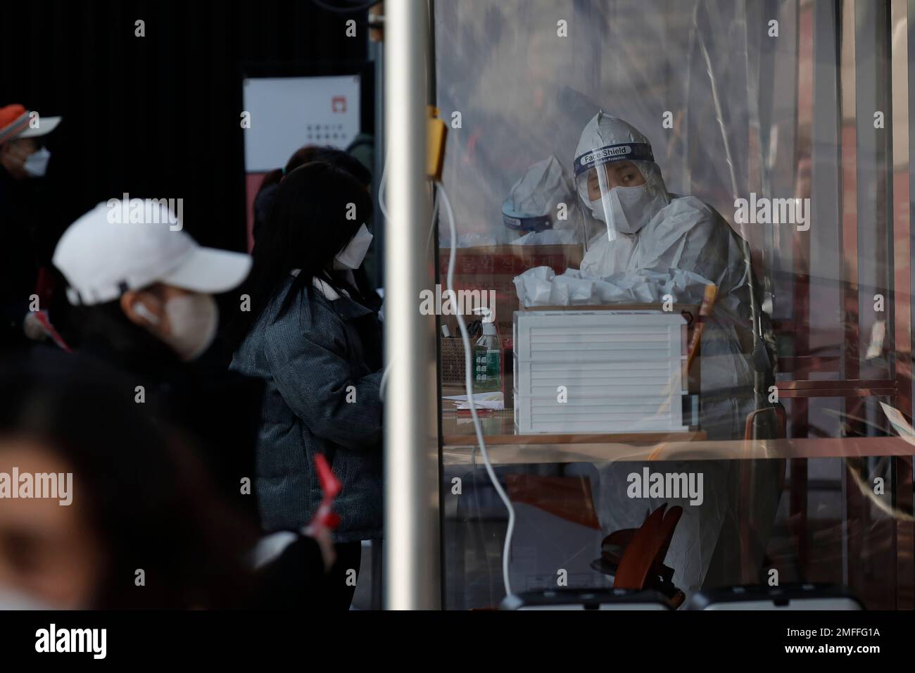 A medical worker wearing protective gear looks at the testing booth at ...