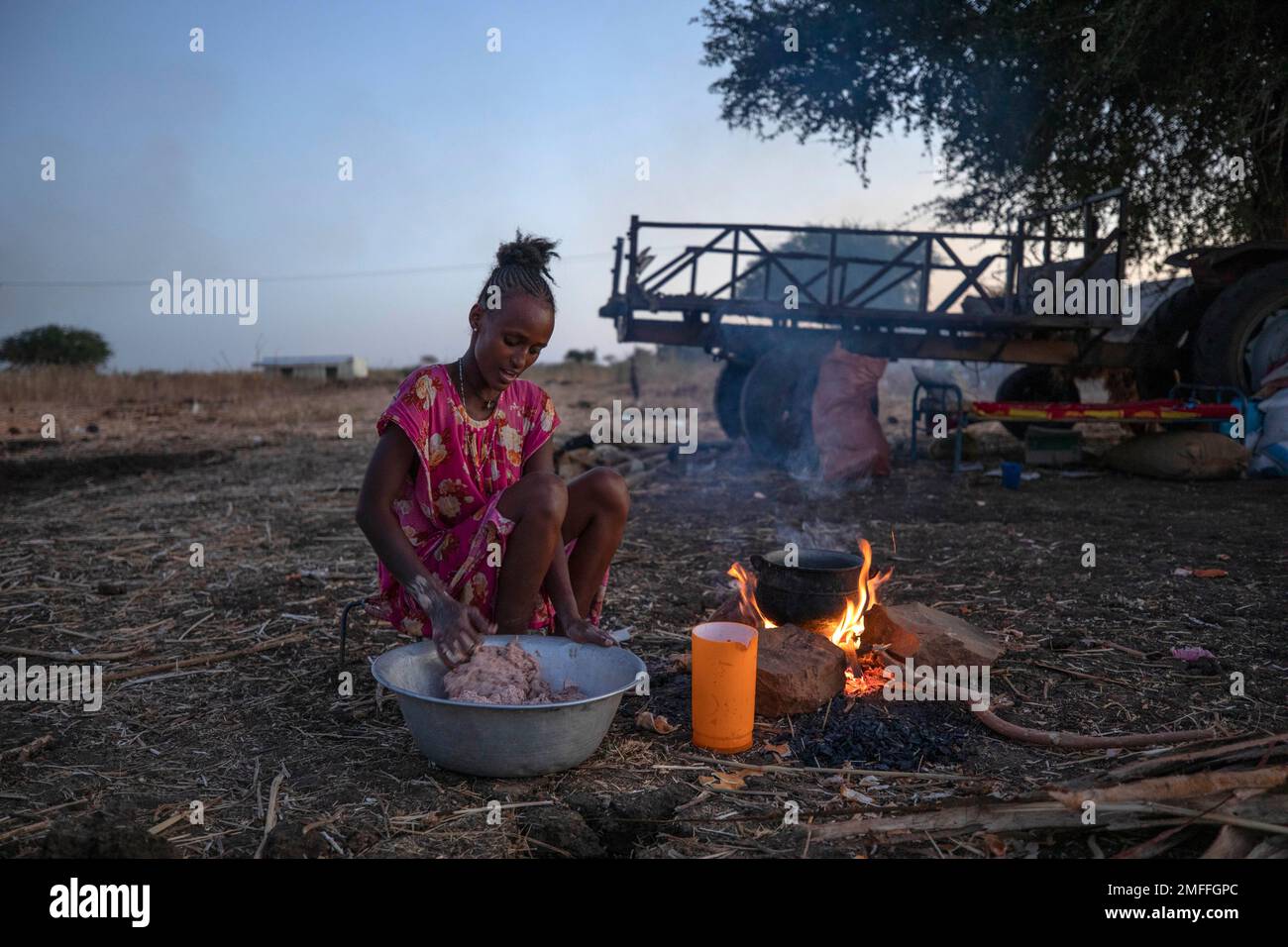 A Tigrinyan refugee woman prepares bread for her family by a lighted ...