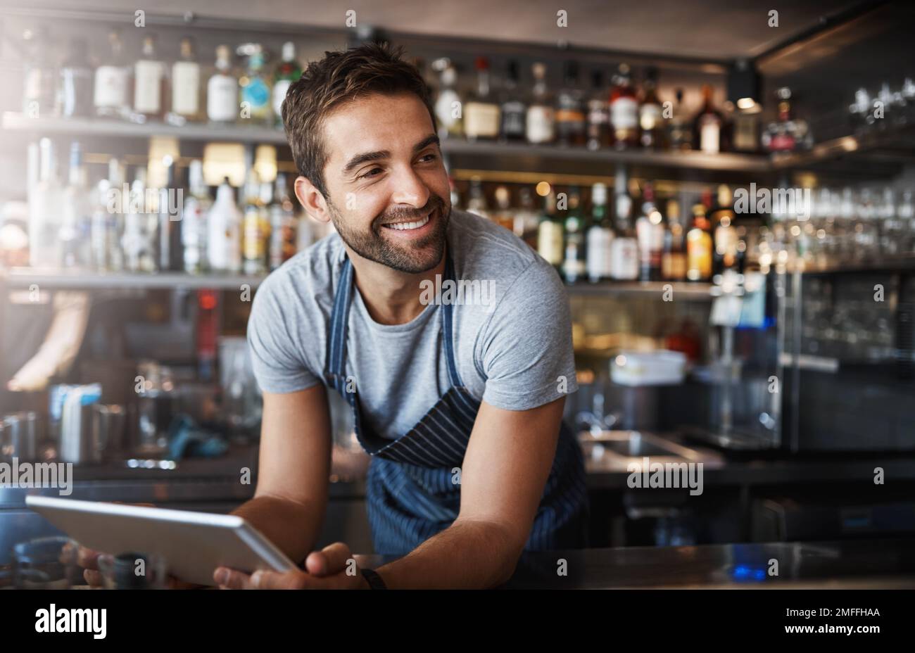 The bar has never been better. a young man using a digital tablet while ...