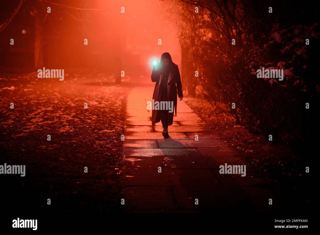 young woman walks through the city at night, illuminating the road with ...