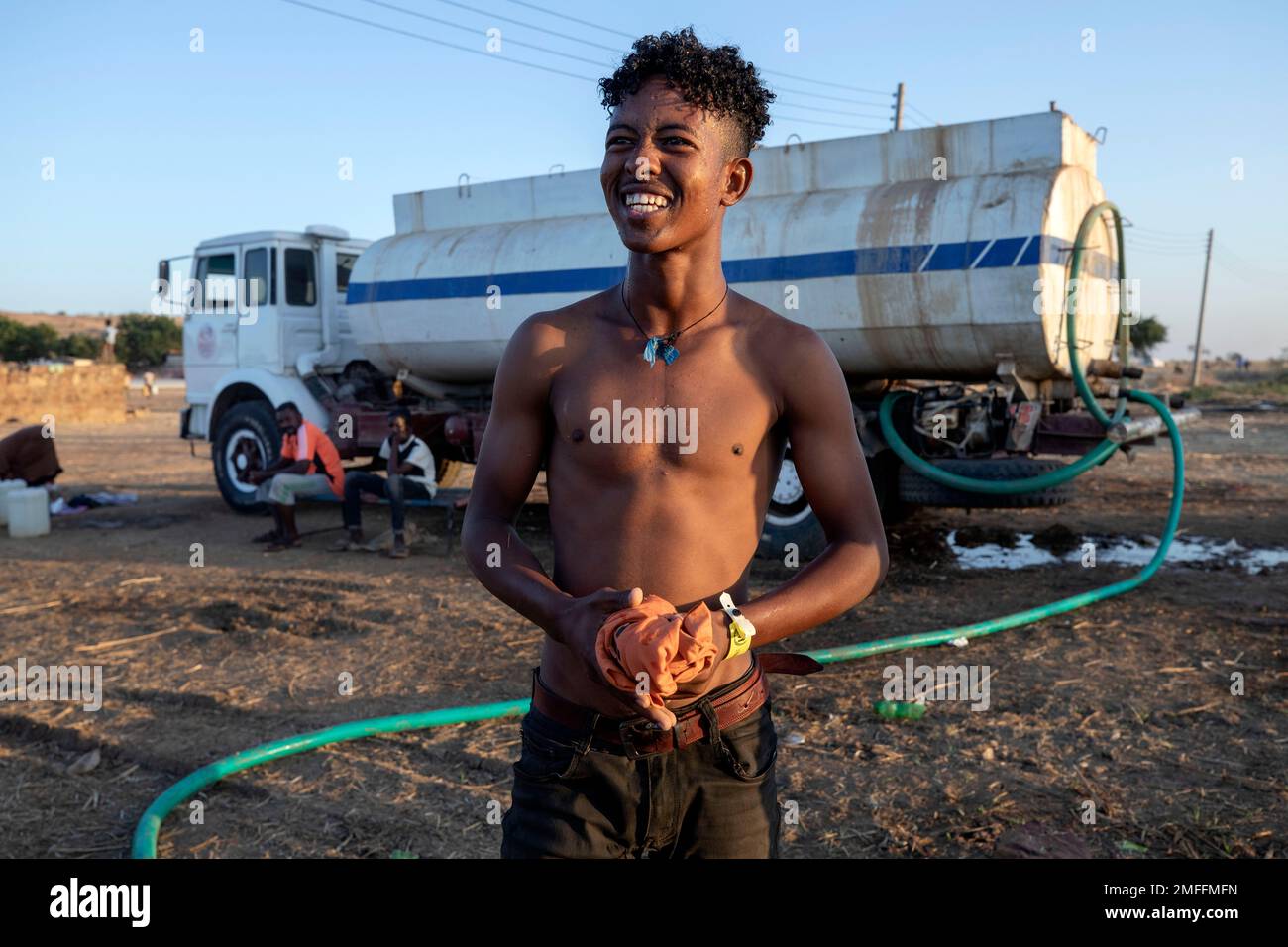A Tigrinyan refugee jokes with his friends after refreshing himself ...