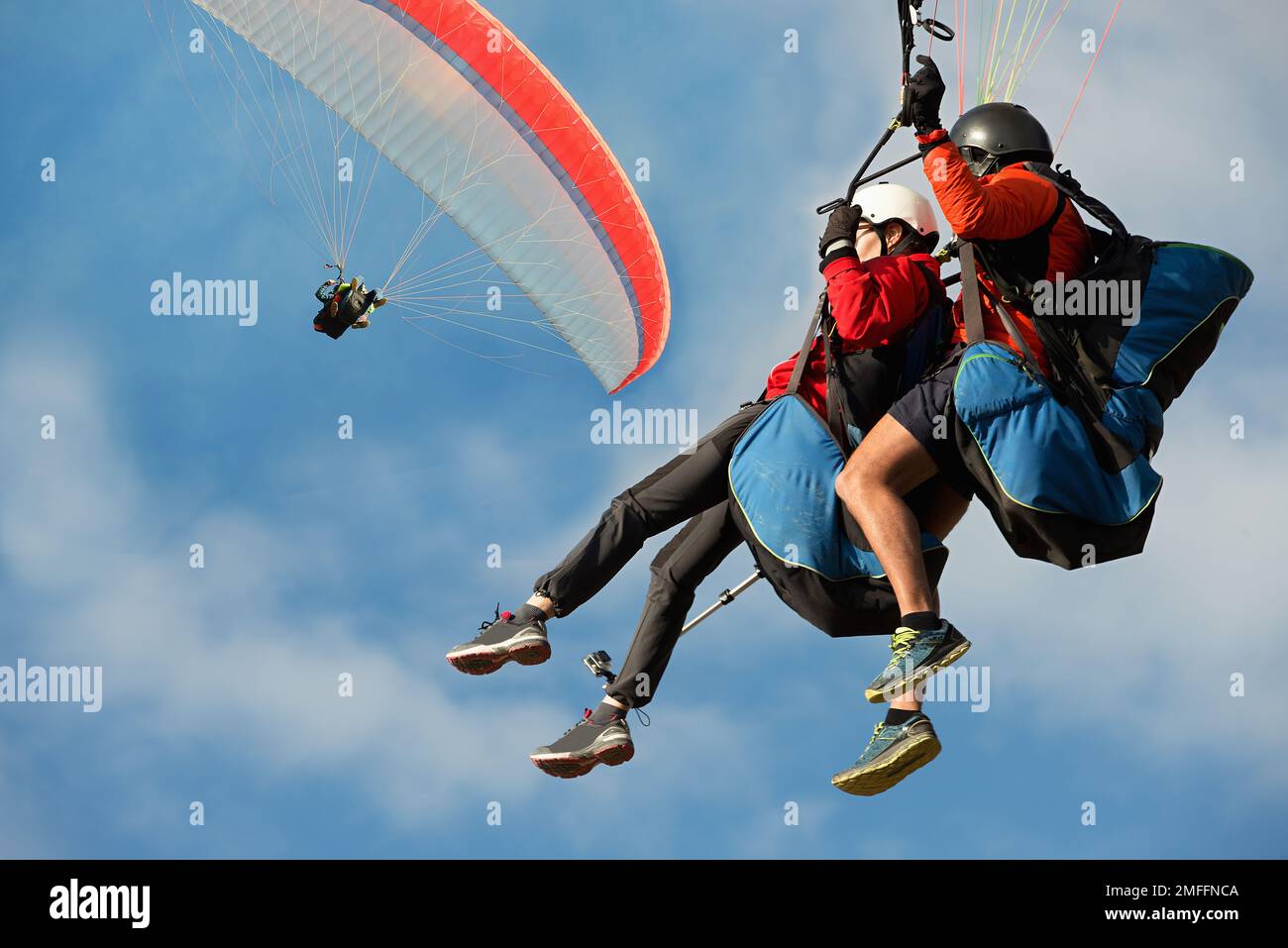 Two paraglider tandem fly against the blue sky, tandem paragliding ...