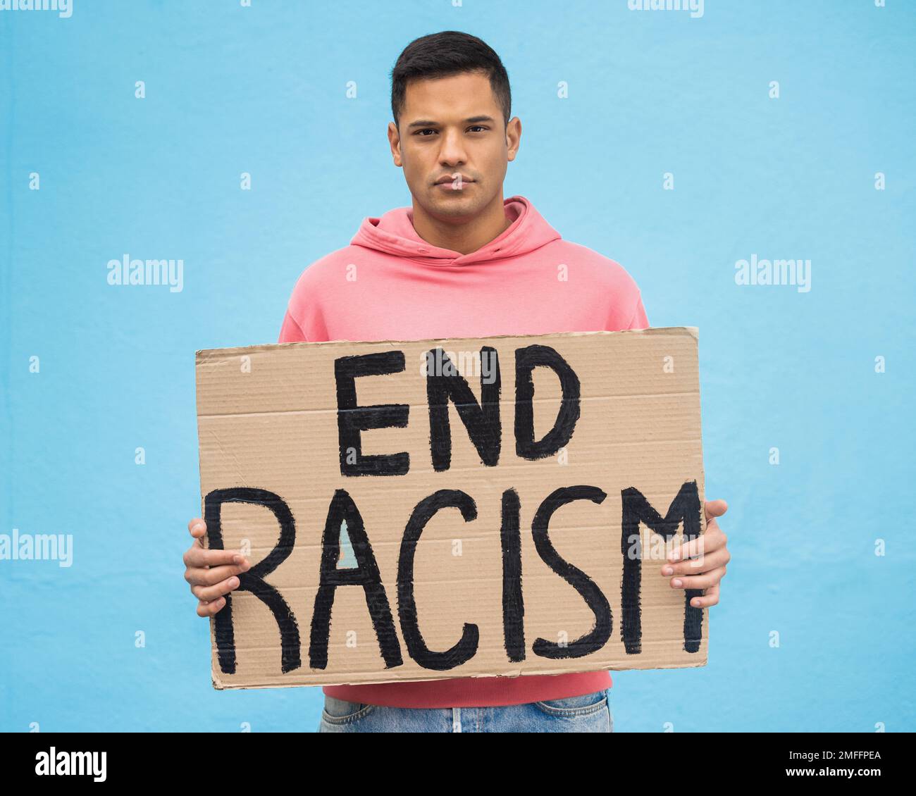 Portrait, sign and racism with a man in studio on a blue background for ...