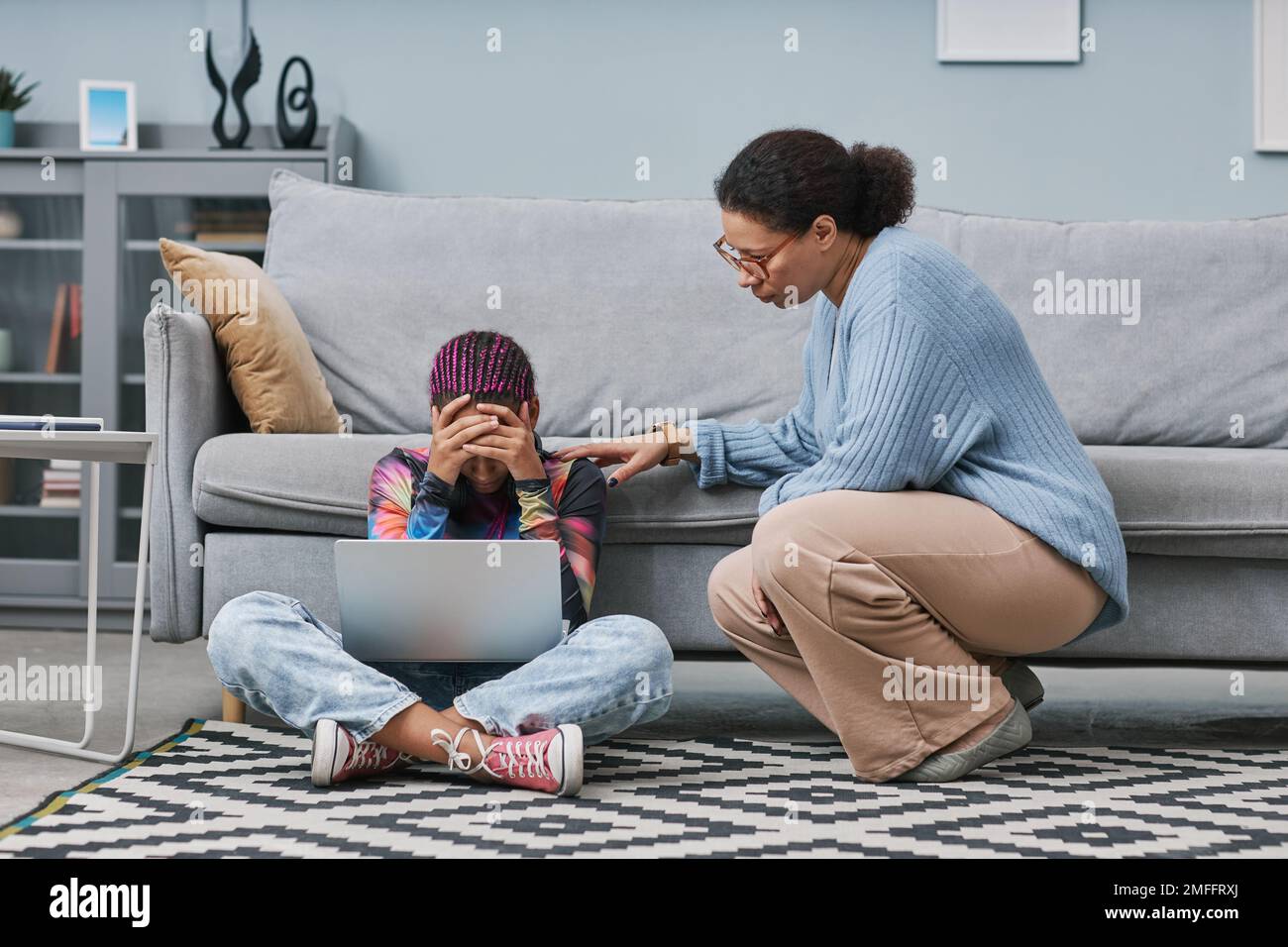 Full length portrait of depressed teenage girl sitting on floor with ...