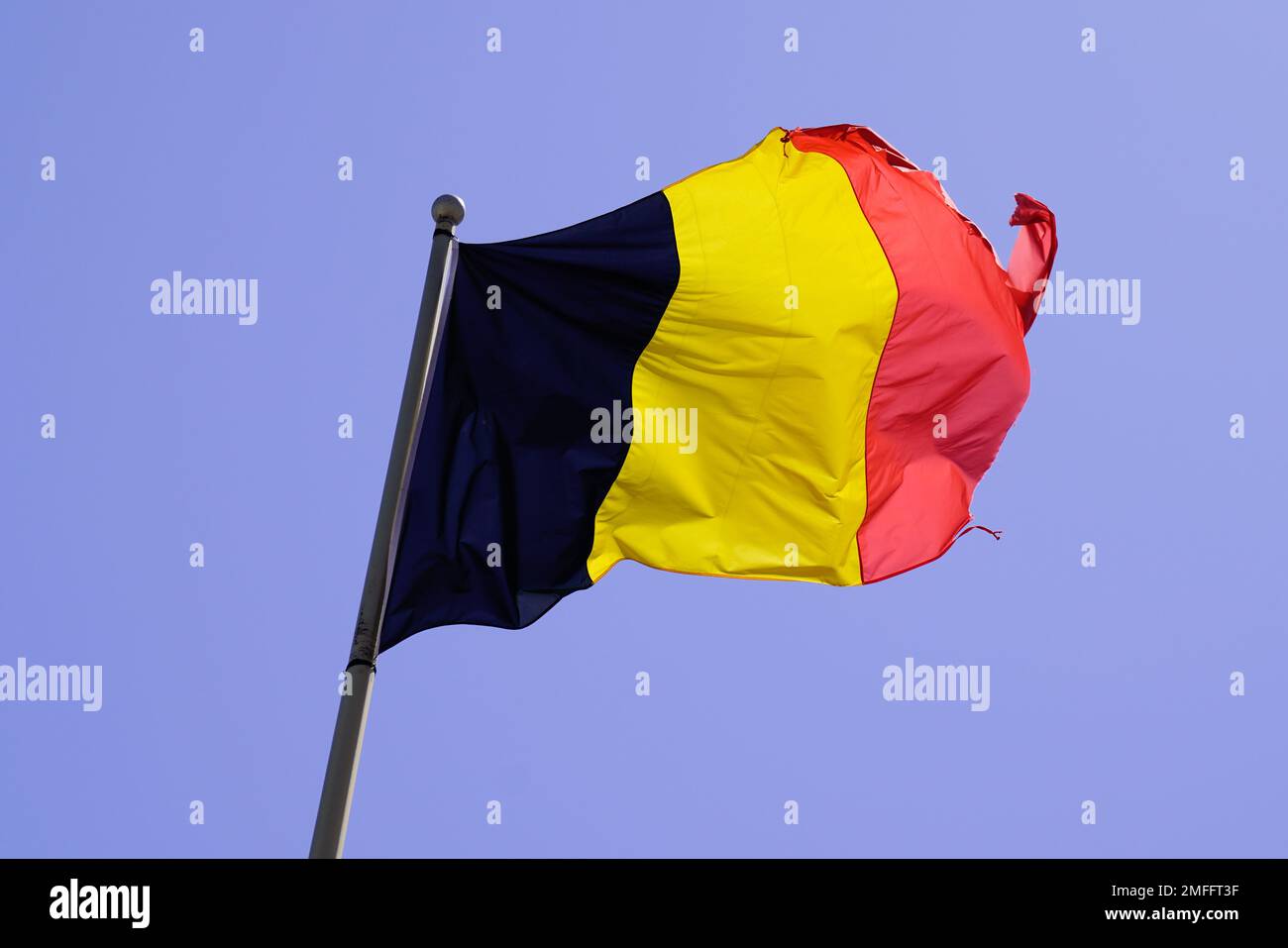 belgium flag belgian wave over a blue sky waving on mat Stock Photo - Alamy