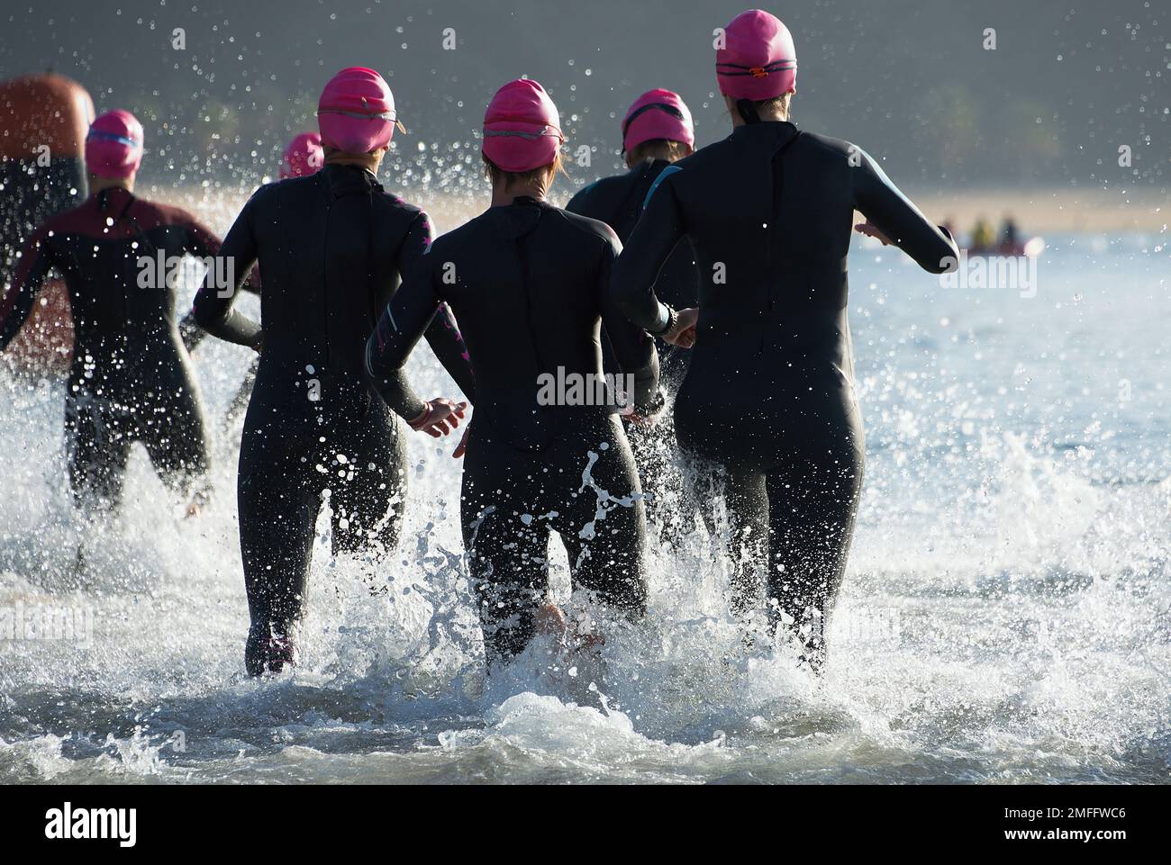 Group triathlon participants running into the water for swim portion of ...