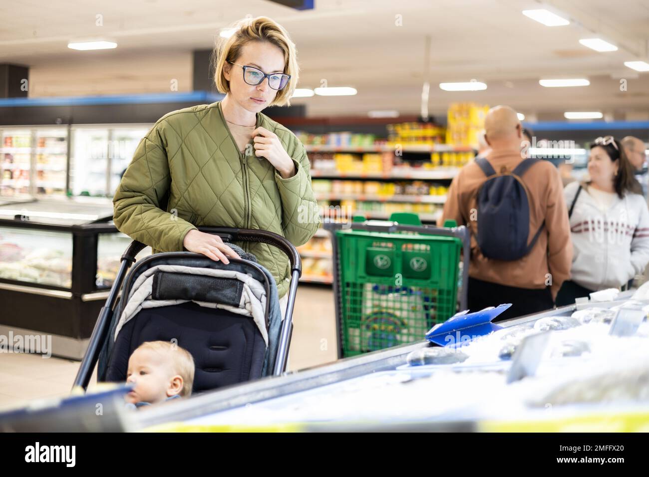 Casualy dressed mother choosing fish in the fish market department of ...