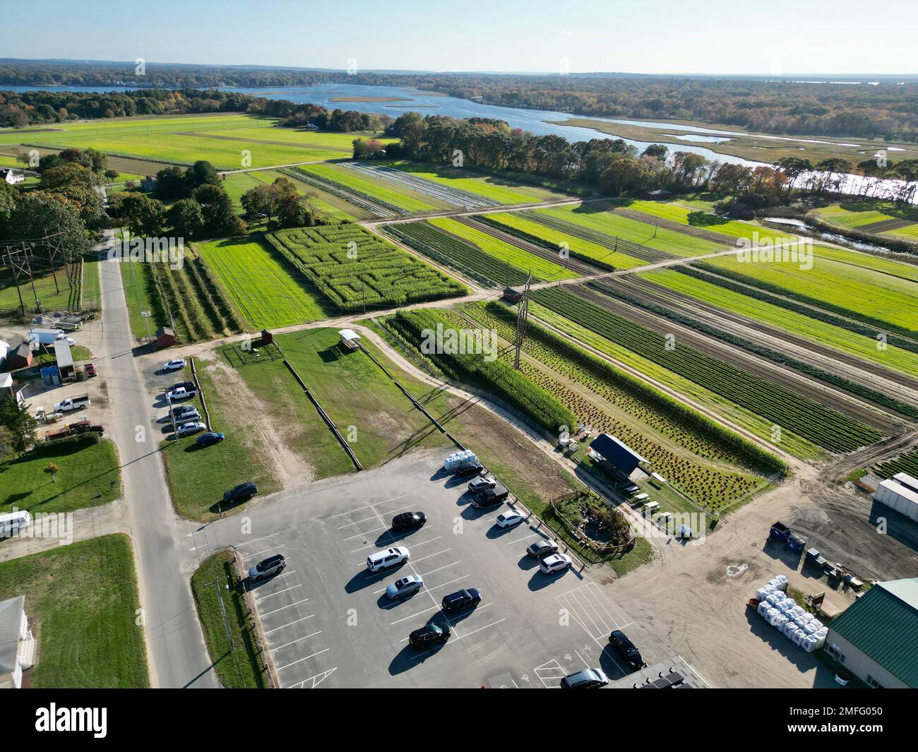 An aerial shot of a parking lot with a calm lake and green fields in ...