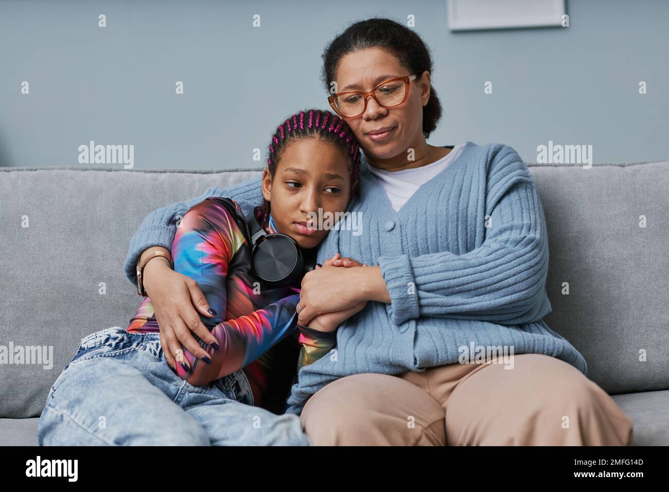 Portrait of mature black woman embracing teenage daughter during ...