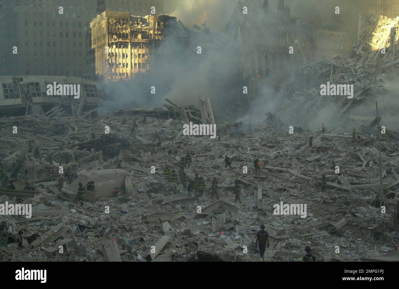 Firefighters walk through smoldering debris at the site of the World ...