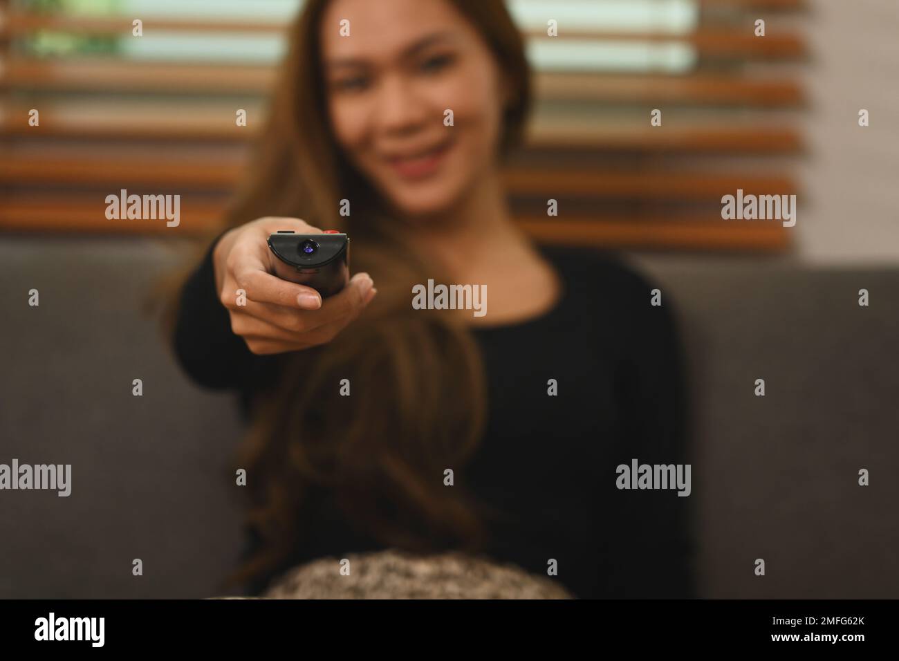 Select focused on hand. Young woman with remote controller watching TV ...