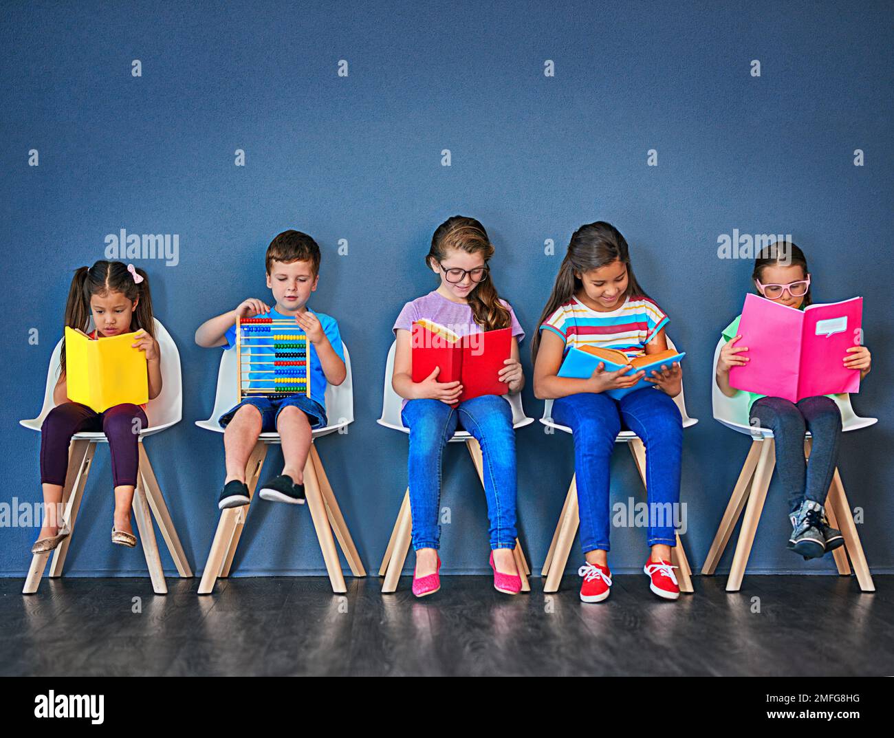 Stay curious. Studio shot of a group of kids sitting on chairs and ...