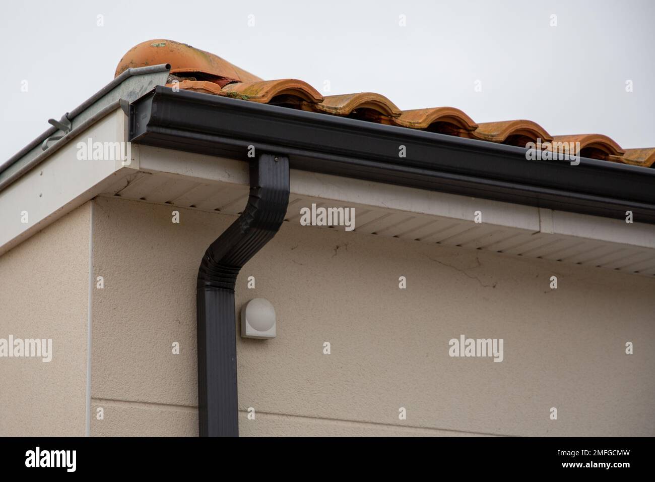metal black gutter on home roof covered with ceramic tiles Close up ...