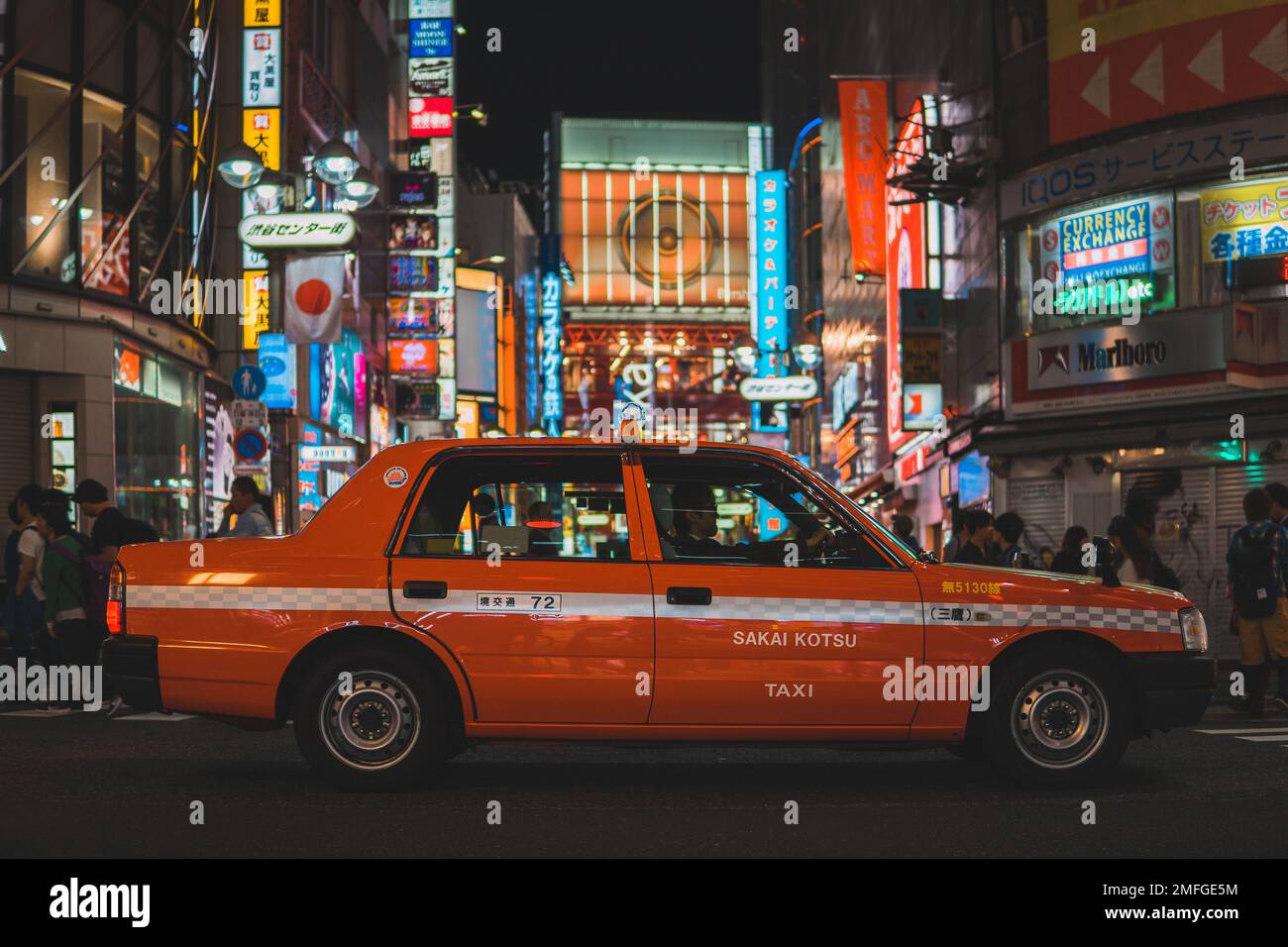 An image of an orange taxi with building and neon lights on a ...