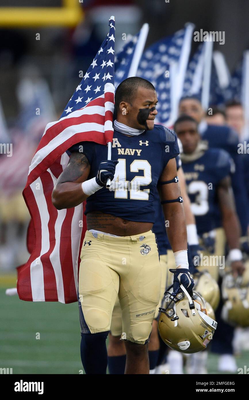 Navy linebacker Ian Blake (42) and others carry american flags before ...