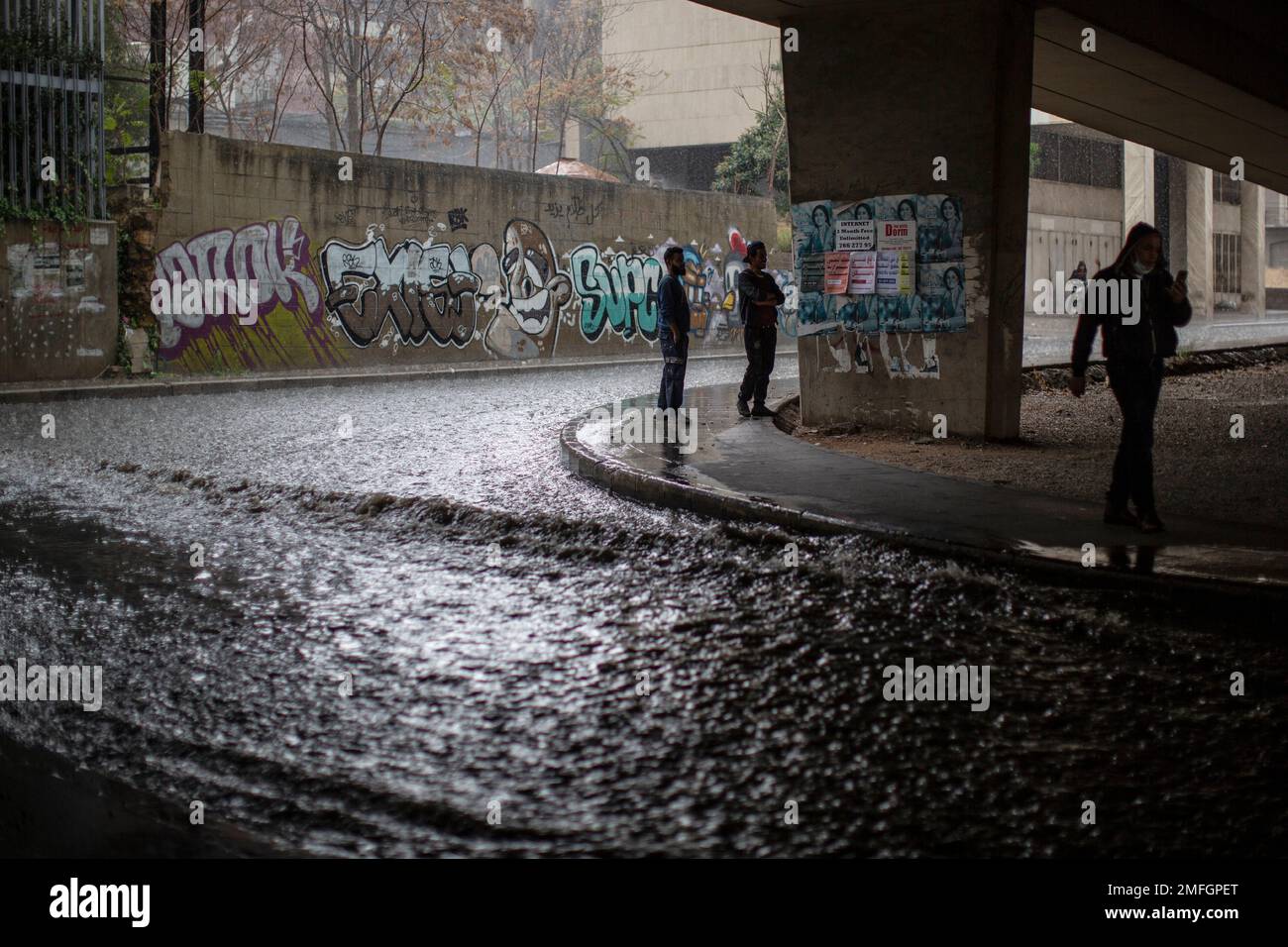 People take cover under a bridge from the heavy fall rain and hail as a ...