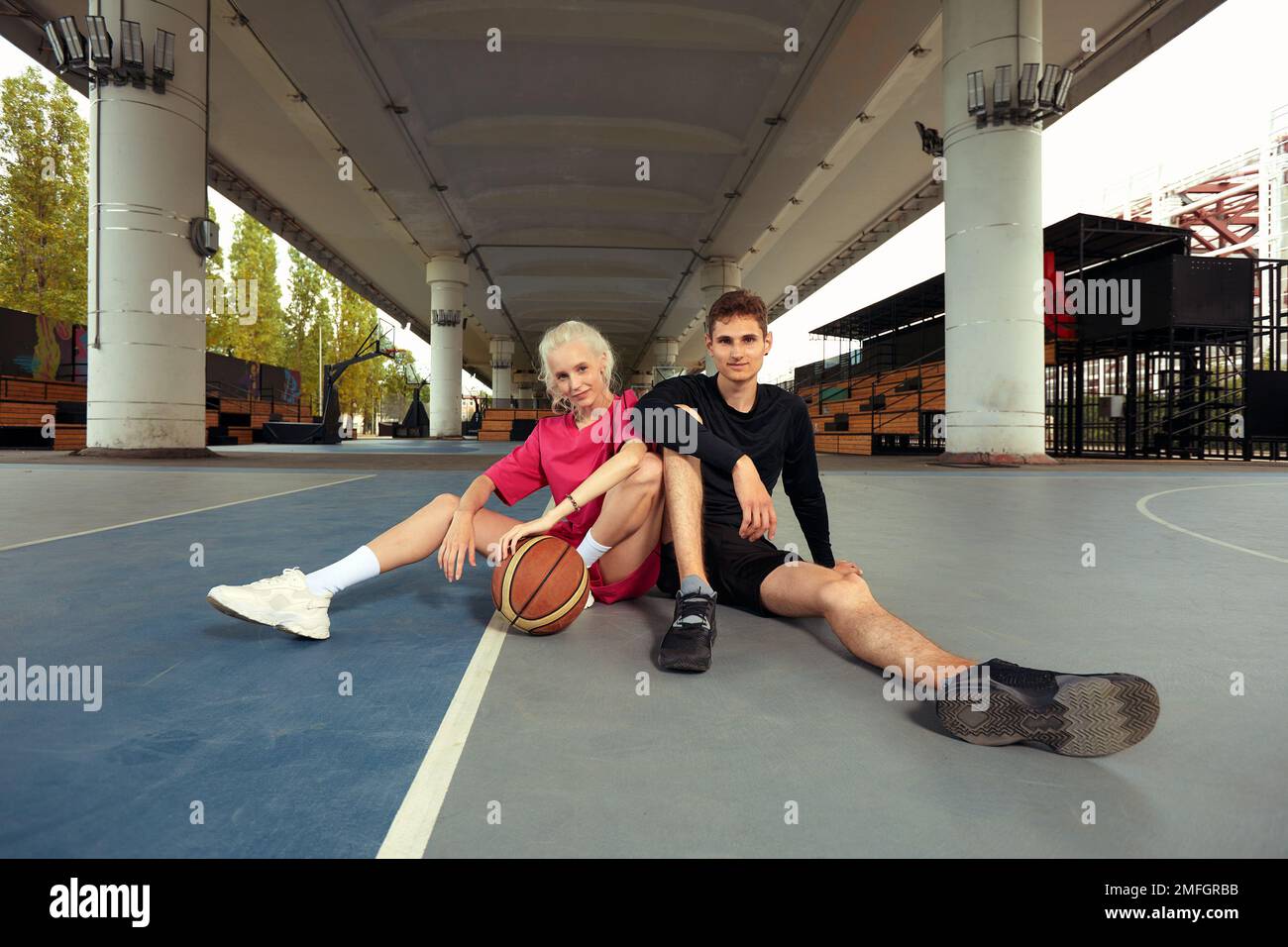 Young girl playing basketball with boy blocking. Teenage friends ...