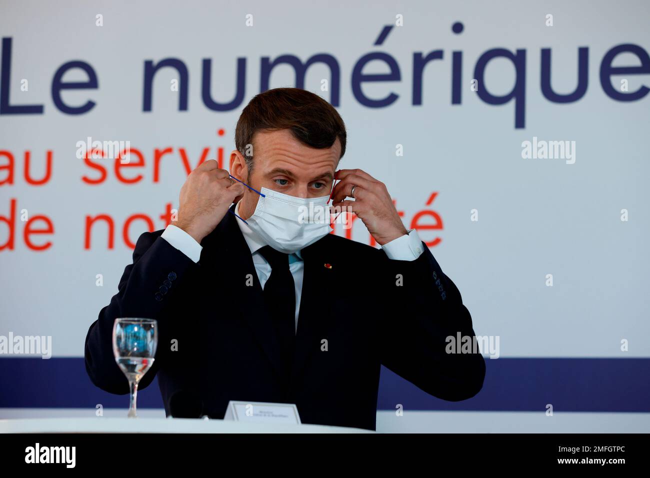French President Emmanuel Macron puts on his masks before his speech on ...