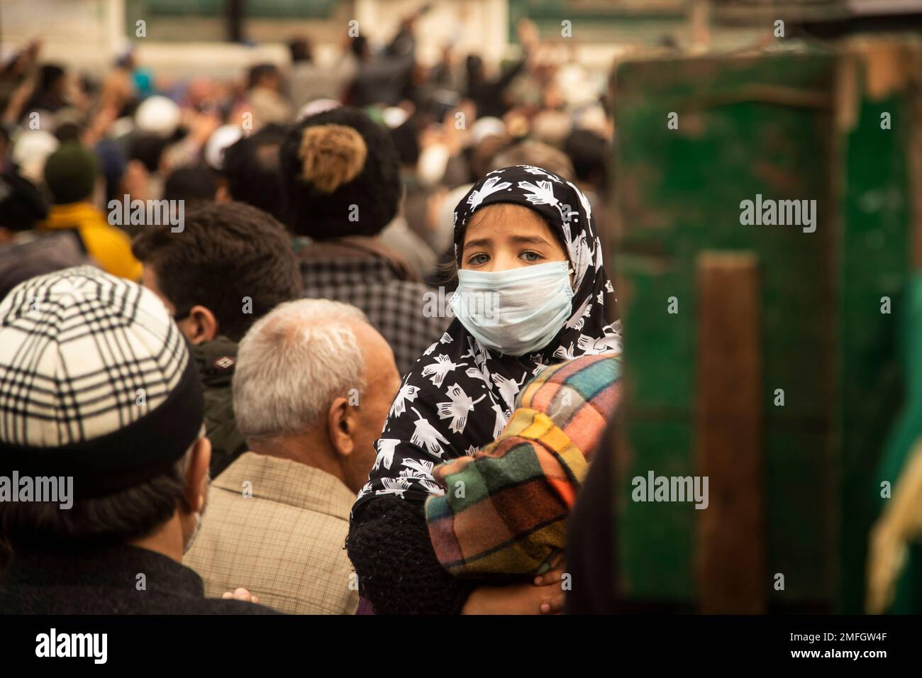 A young Kashmiri Muslim girl wearing a face mask joins devout outside ...
