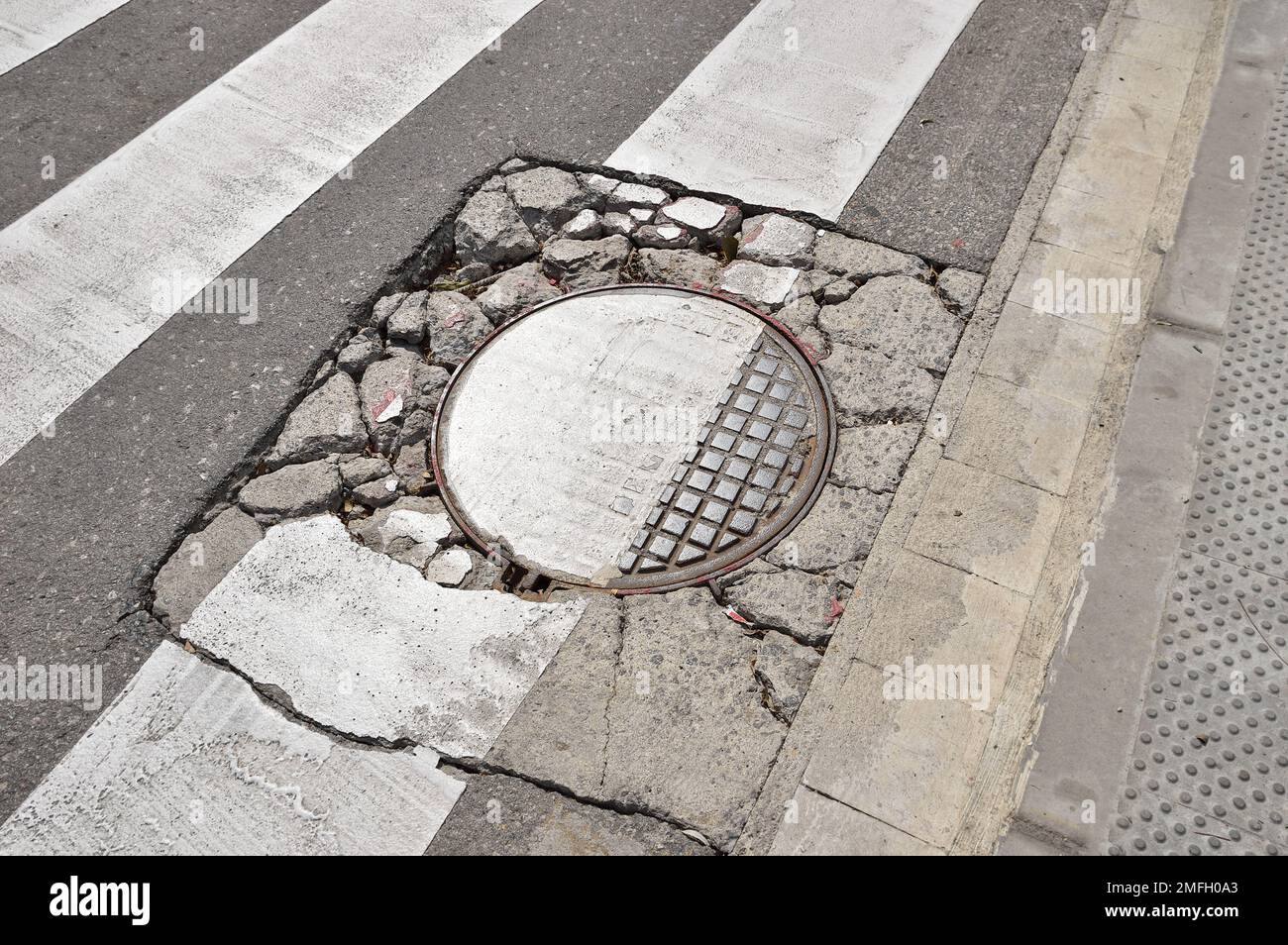 large pit with stones on the asphalt highway with old broken manhole ...