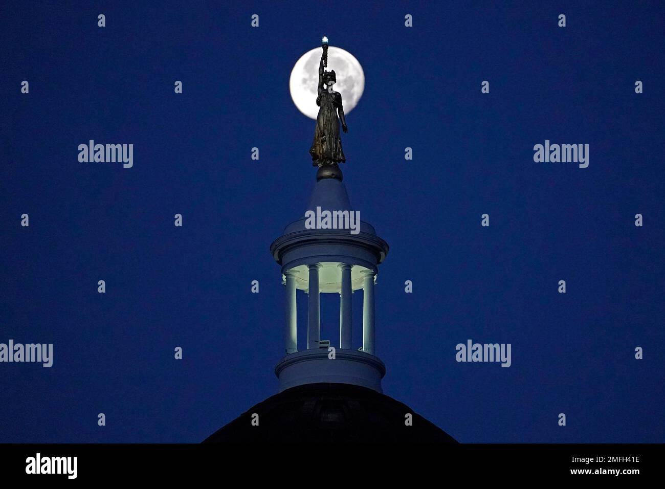 The waning moon sets behind the Lady of Wisdom at the top of the State ...