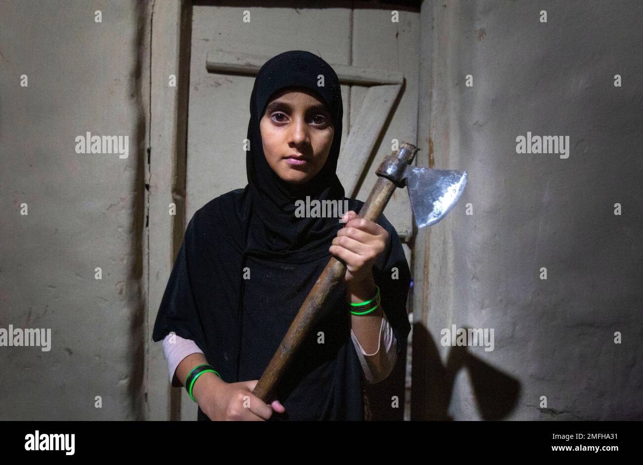 Kashmiri girl Muskan, 14, displays outside her home an axe that the ...