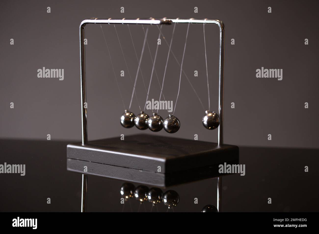 Closeup metal Newton cradle placed on gray background as representation ...