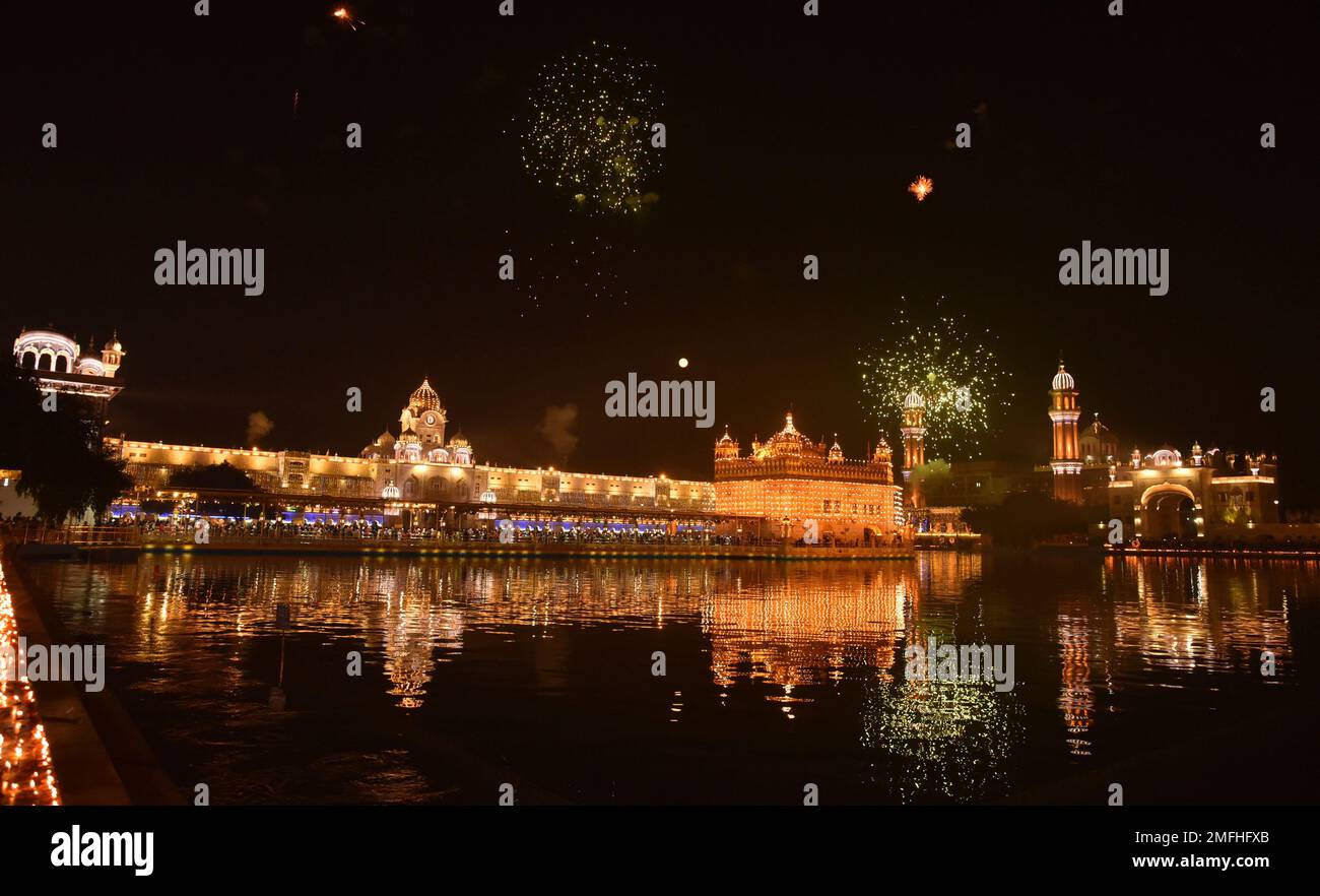 People watch a fireworks display over the illuminated Golden Temple ...