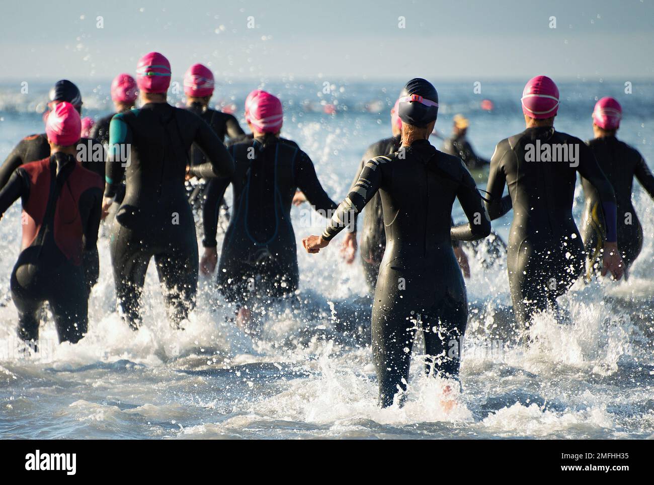 Group triathlon participants running into the water for swim portion of ...