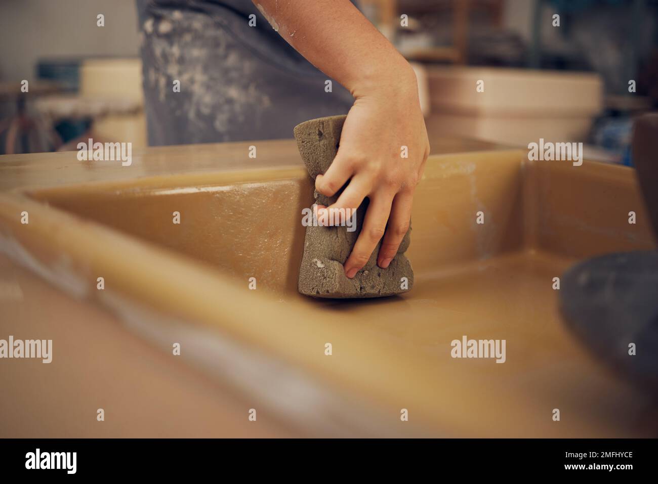 Hand, pottery and sponge with a woman in her workshop or studio to ...