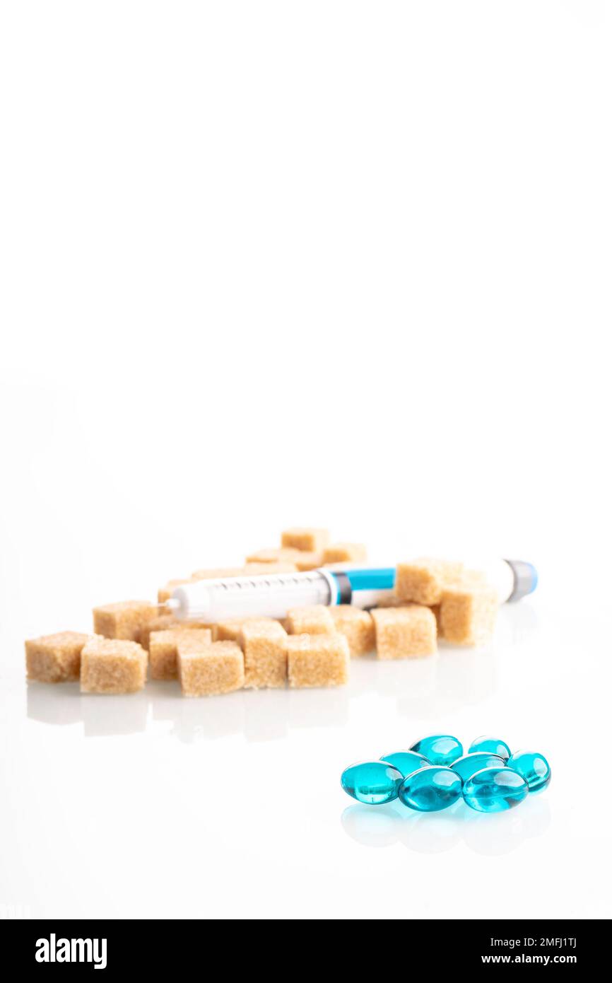 A vertical shot of blue vitamin capsules with insulin pen and brown ...