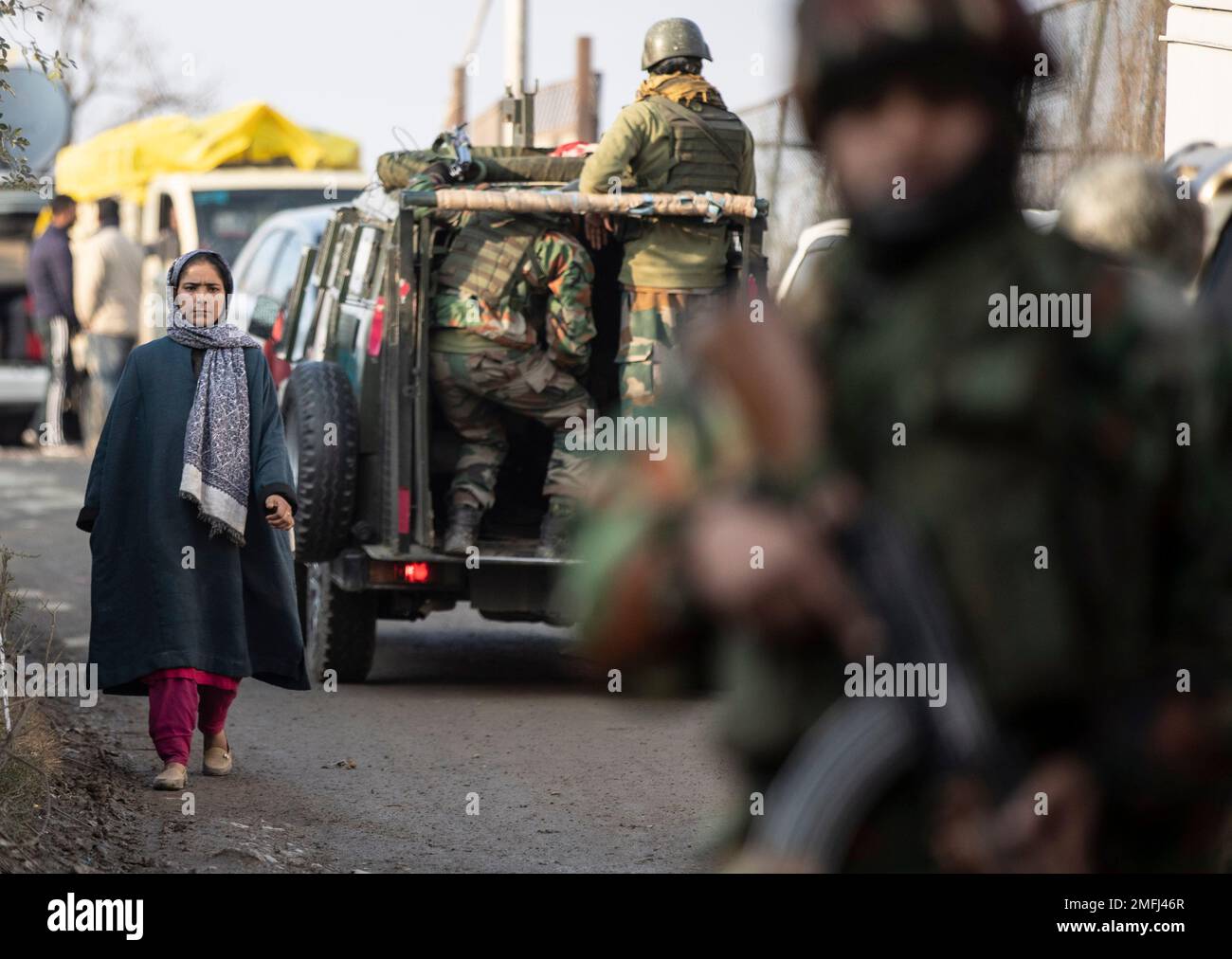 A Kashmiri woman walks past security officers keeping guard near the ...