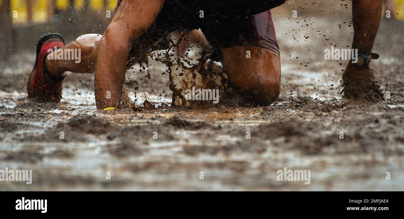 Mud race runners. Crawling,passing under a barbed wire obstacles during ...