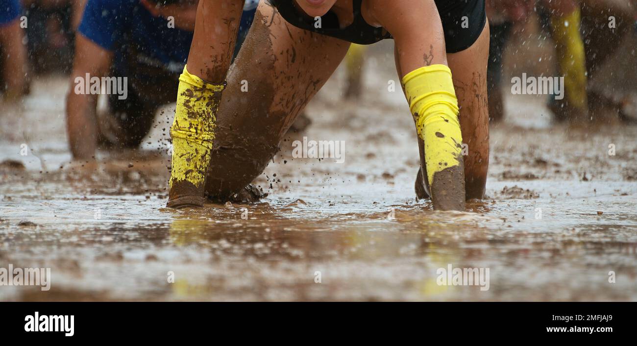 Mud race runners. Crawling,passing under a barbed wire obstacles during ...
