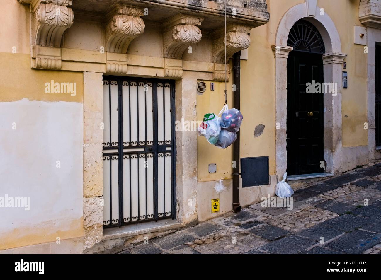 A bag of rubbish for collection hangs in an alley in the Late Baroque ...