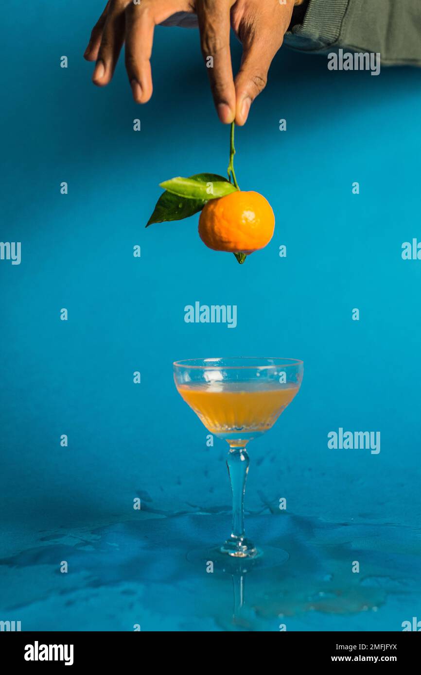 man's hand holding mandarin tangerine orange fruit dropping into ...