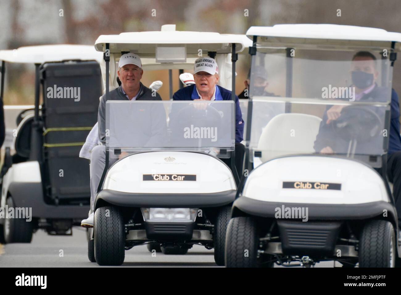 President Donald Trump, center, drives a golf cart as he golfs at Trump ...