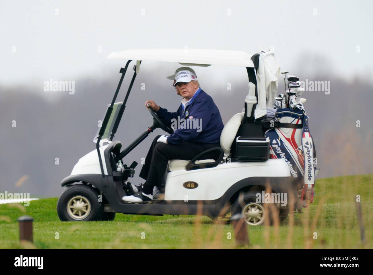 President Donald Trump drives a golf cart as he golfs at Trump National ...
