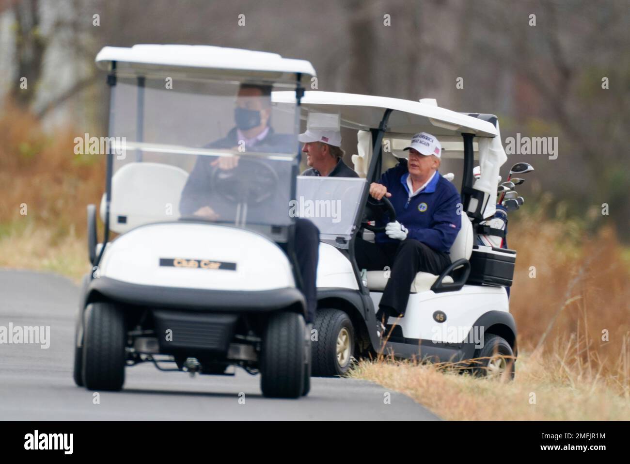 President Donald Trump drives a golf cart as he golfs at Trump National ...